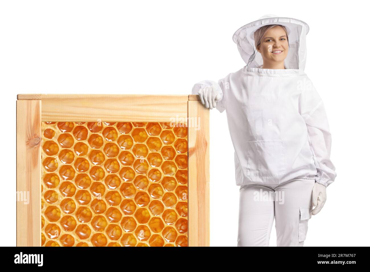 Female bee keeper in a uniform leaning on a big honeycomb frame ...