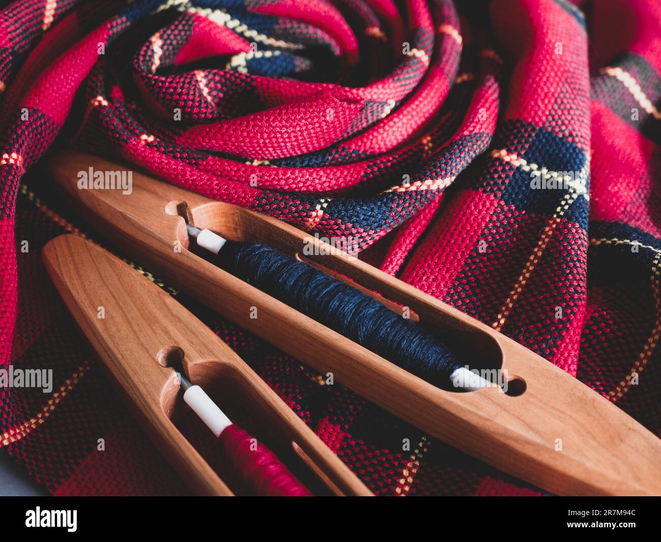 Two boat shuttles and handwoven fabric in red and black colors, close ...