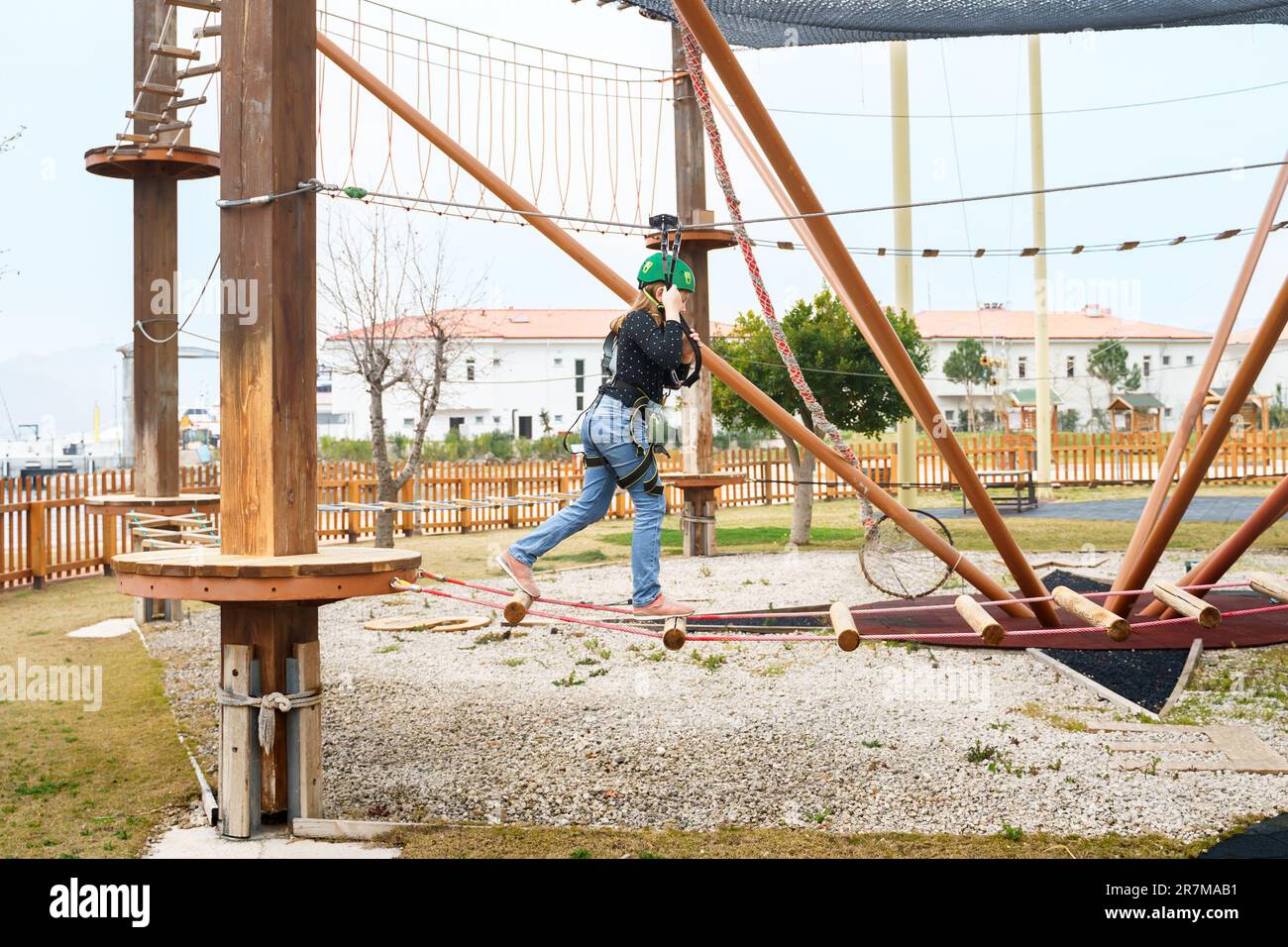 Teenage teen girl in climbing harness equipment, green sports safety ...