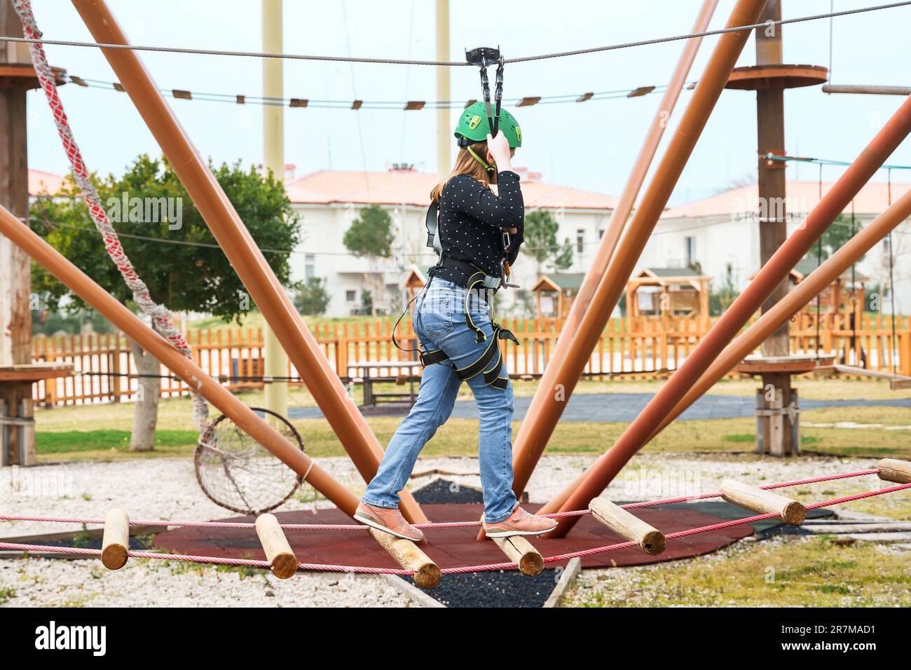 Teenage teen girl in climbing harness equipment, green sports safety ...