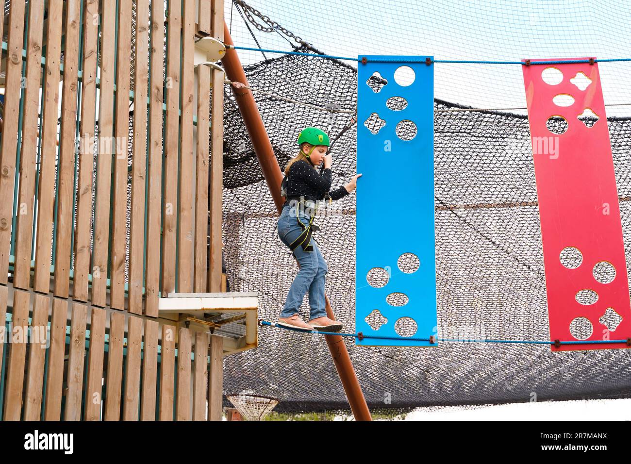 Teenage teen girl in climbing harness equipment, green sports safety ...