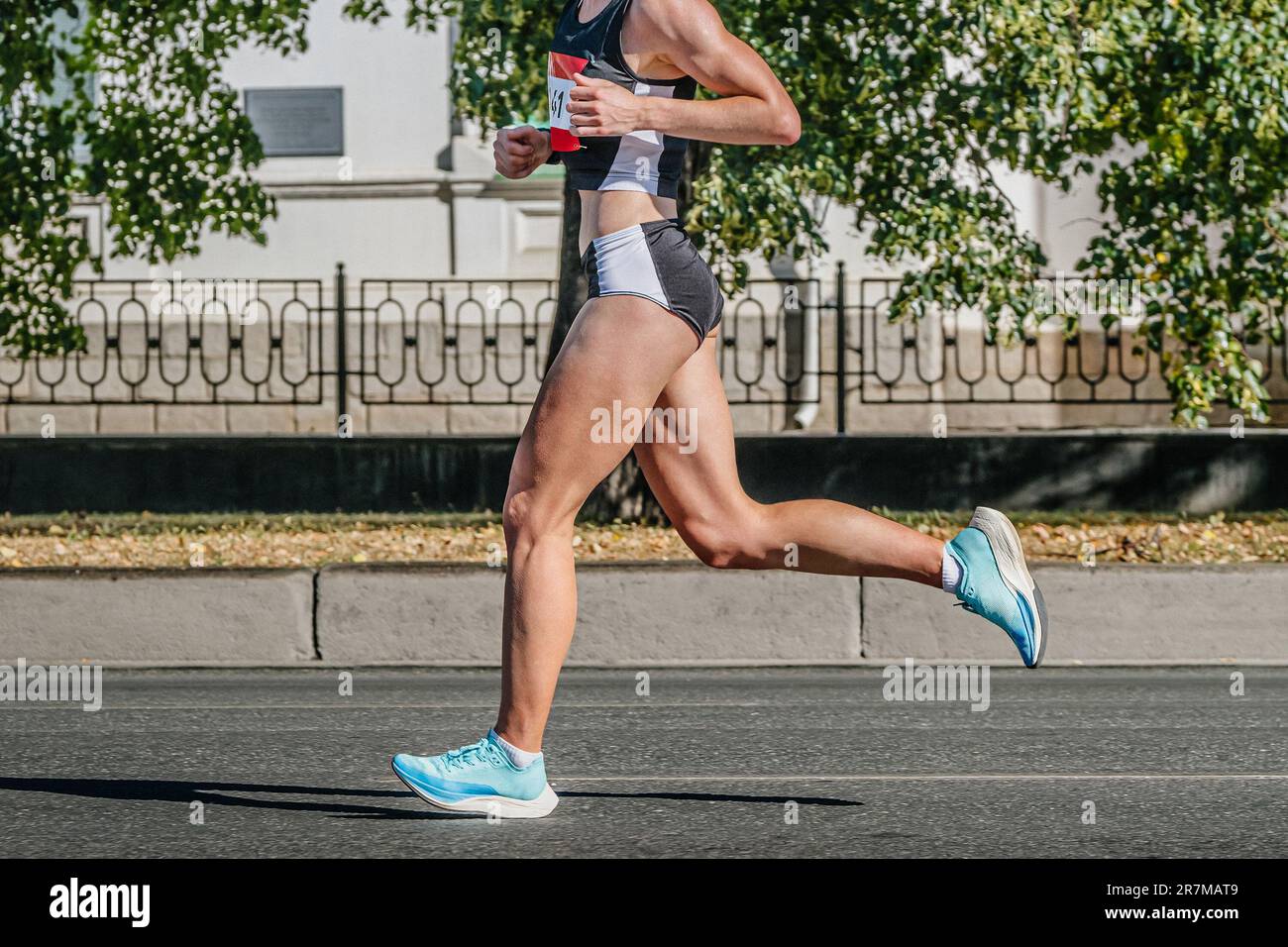 side view female runner athlete running city marathon race, summer ...