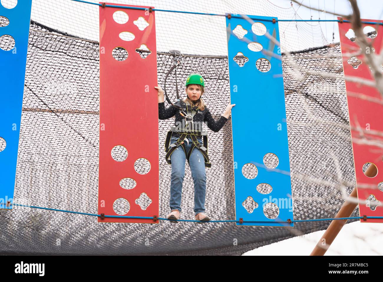 Teenage teen girl in climbing harness equipment, green sports safety ...