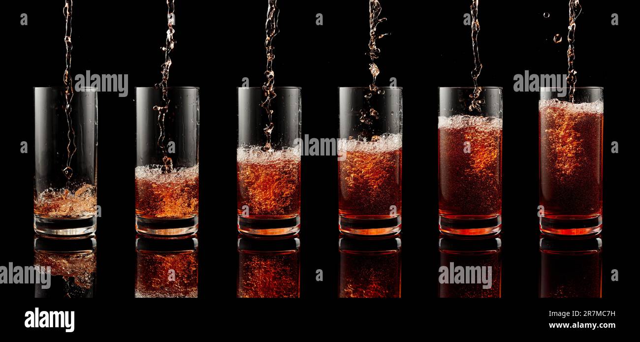 Pouring carbonated drink into a glass on a black reflective background Stock Photo - Alamy
