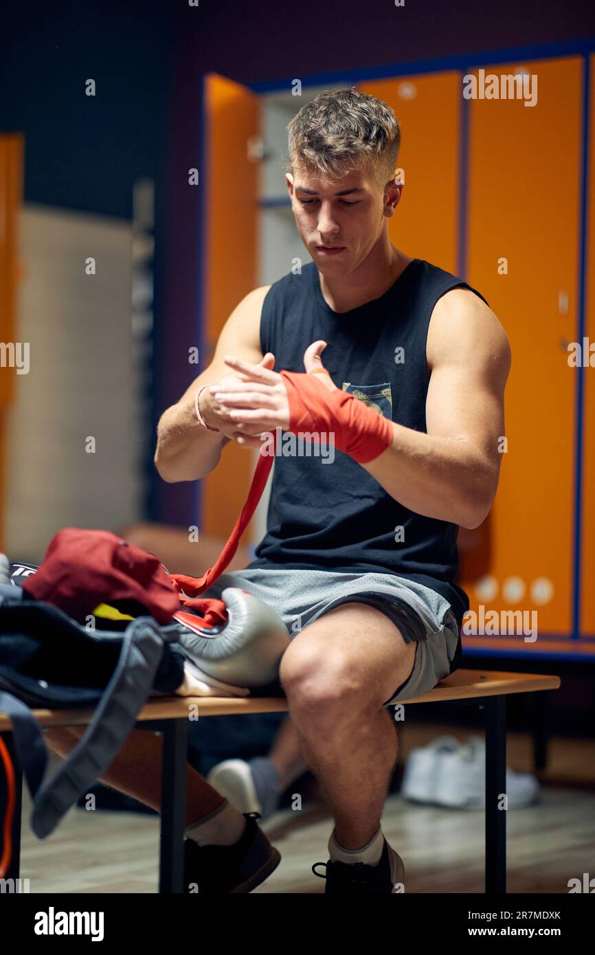 Handsome young man sitting in dressing room, focusing while tying tape ...