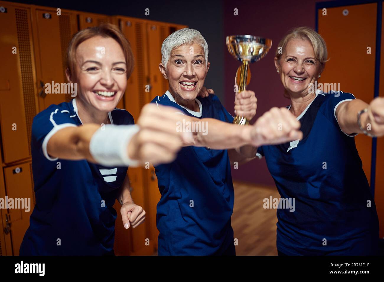 Female sports team of three celebrating together in locker room ...