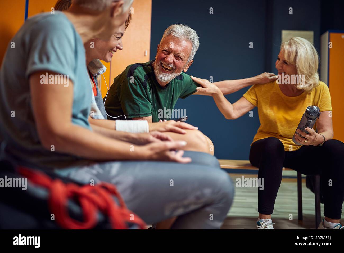 Group of four people in gym locker room, senior man and women talking ...
