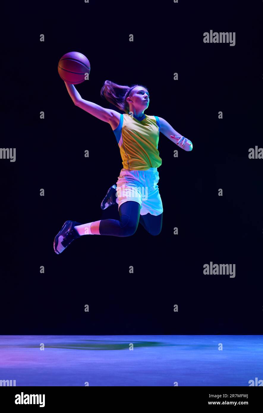 Slam dunk. Basketball player in motion, young girl jumping with ball ...