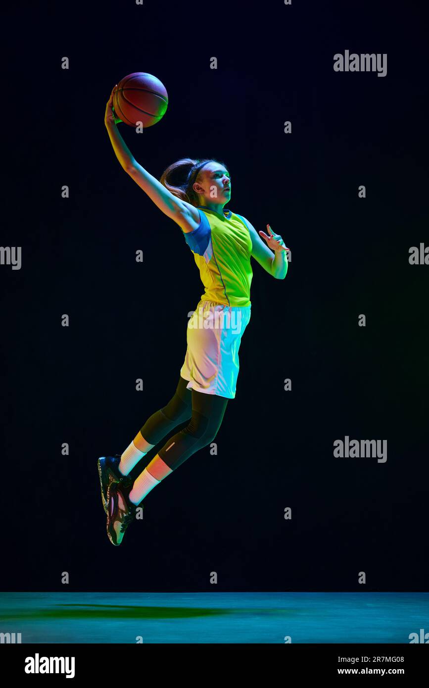 Slam dunk. Female basketball player in motion, jumping with ball ...