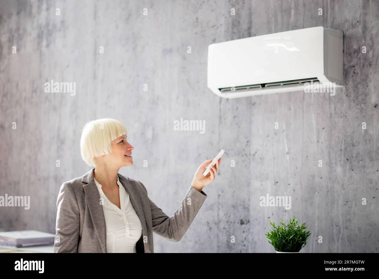 Happy Young Woman Using Air Conditioner With Remote Stock Photo - Alamy