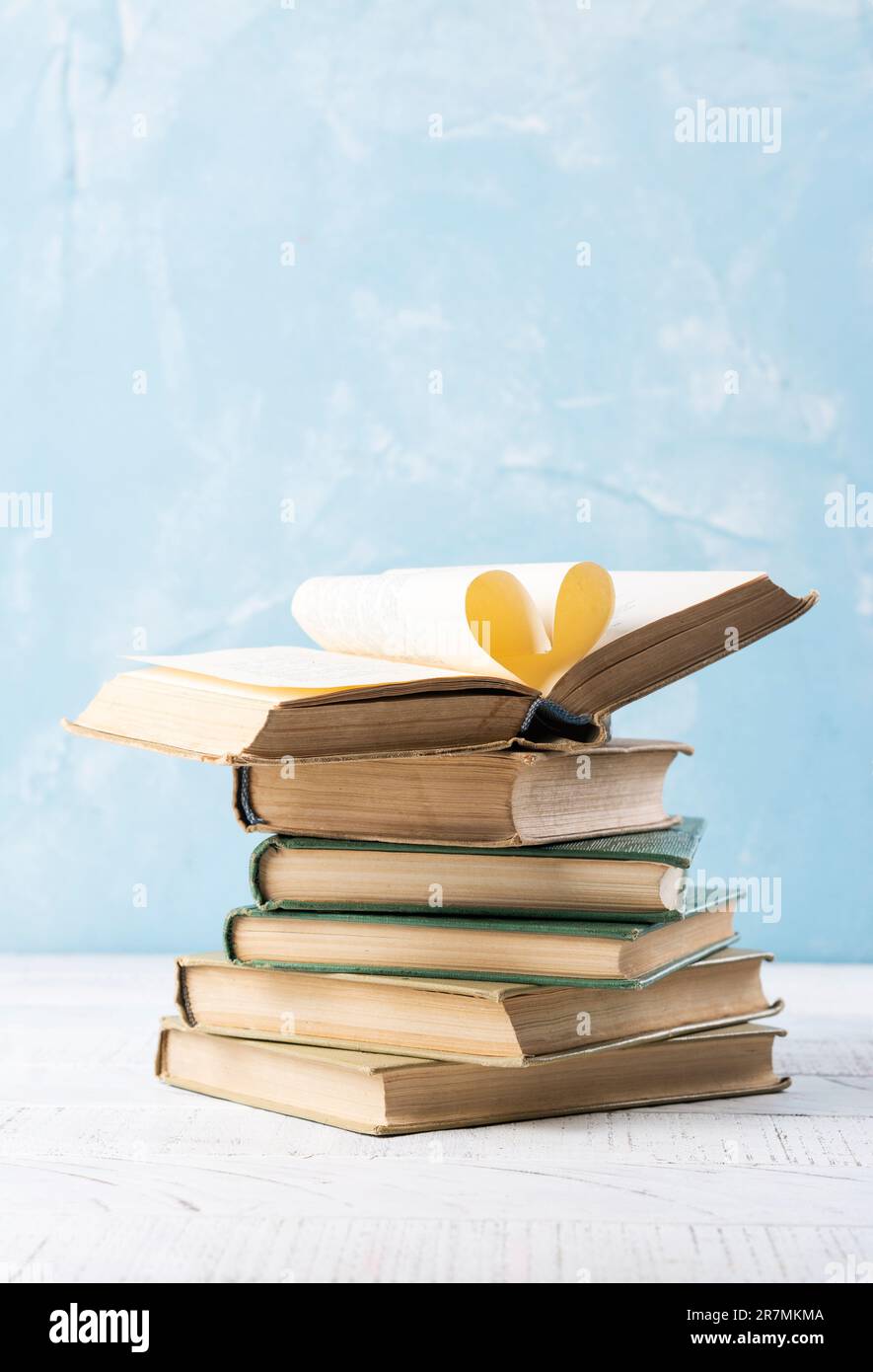 Book with opened pages in shape of heart and stacked books on reading ...