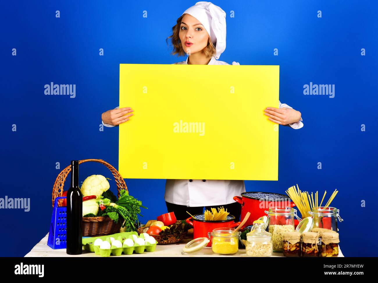 Smiling chef with empty yellow board. Business lunch menu. Cook with ...