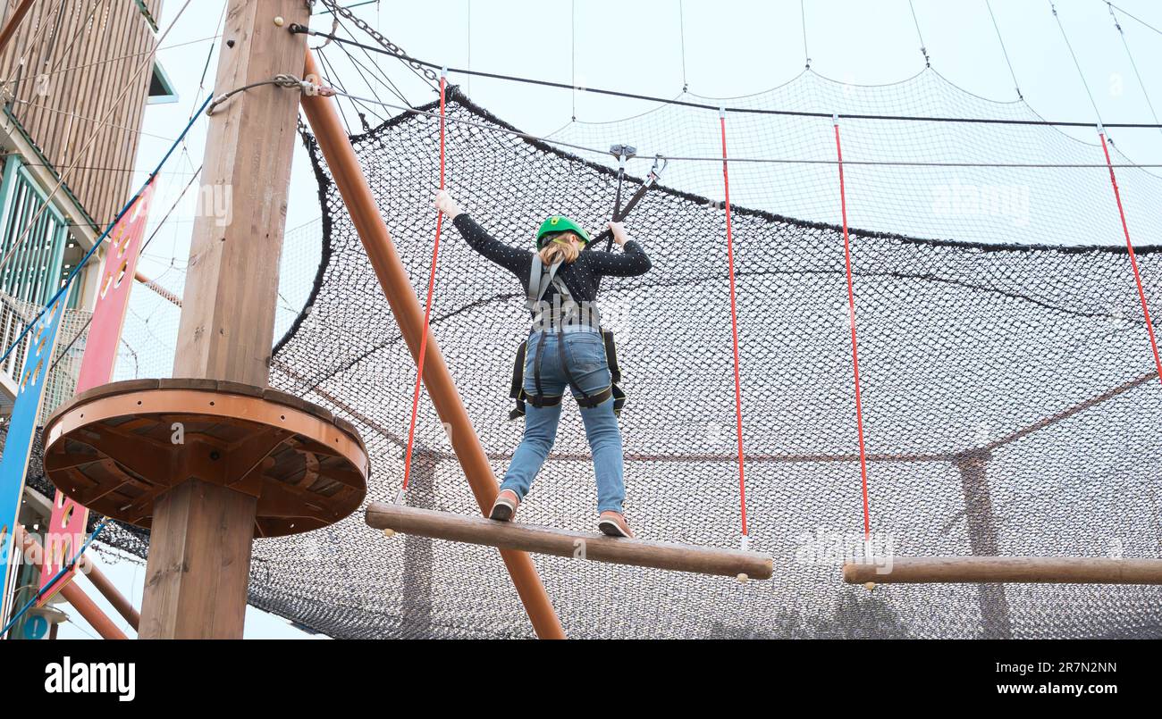 Teenage teen girl in climbing harness equipment, green sports safety ...