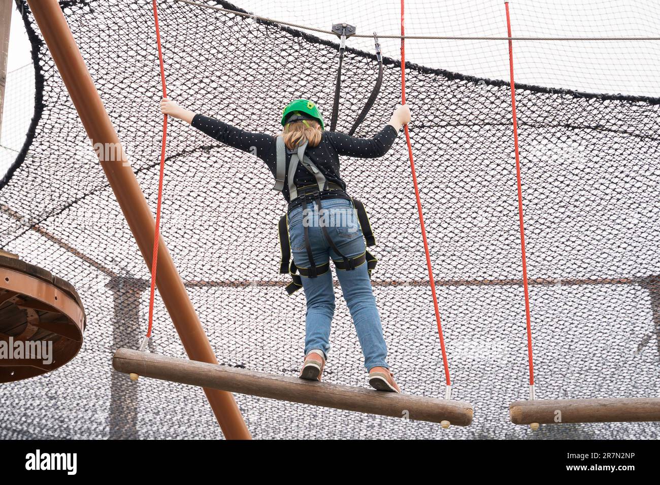 Teenage teen girl in climbing harness equipment, green sports safety ...
