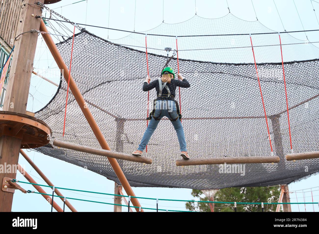 Teenage teen girl in climbing harness equipment, green sports safety ...