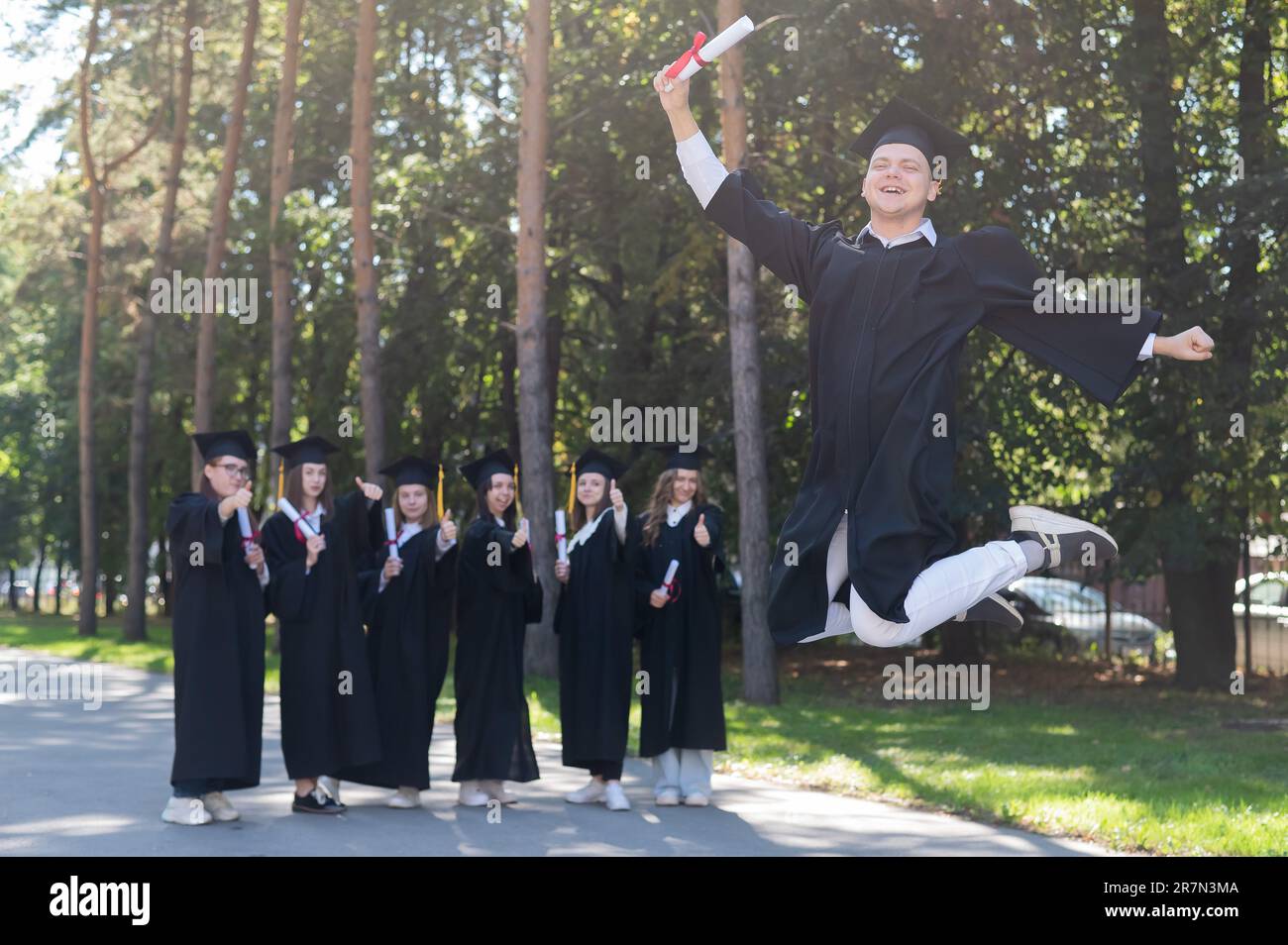 Happy young caucasian man celebrating graduation. Crowd of students ...