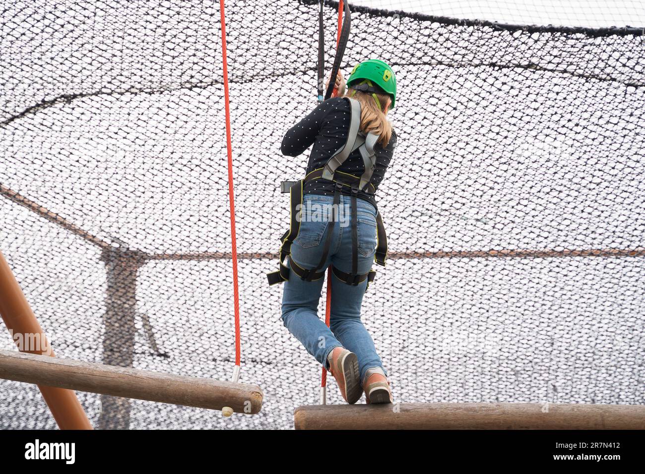 Teenage teen girl in climbing harness equipment, green sports safety ...
