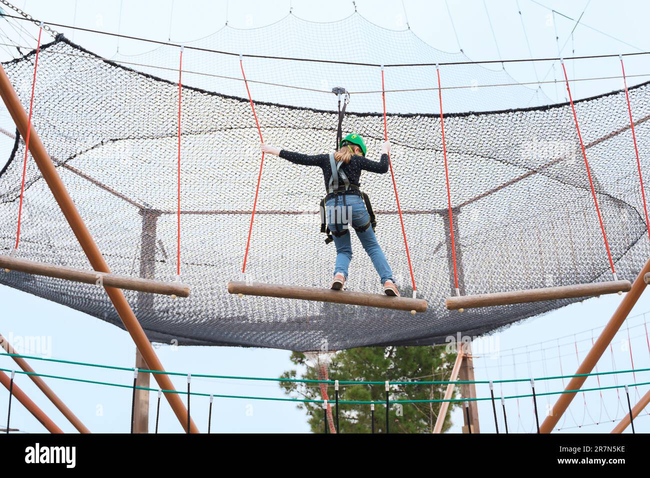 Teenage teen girl in climbing harness equipment, green sports safety ...
