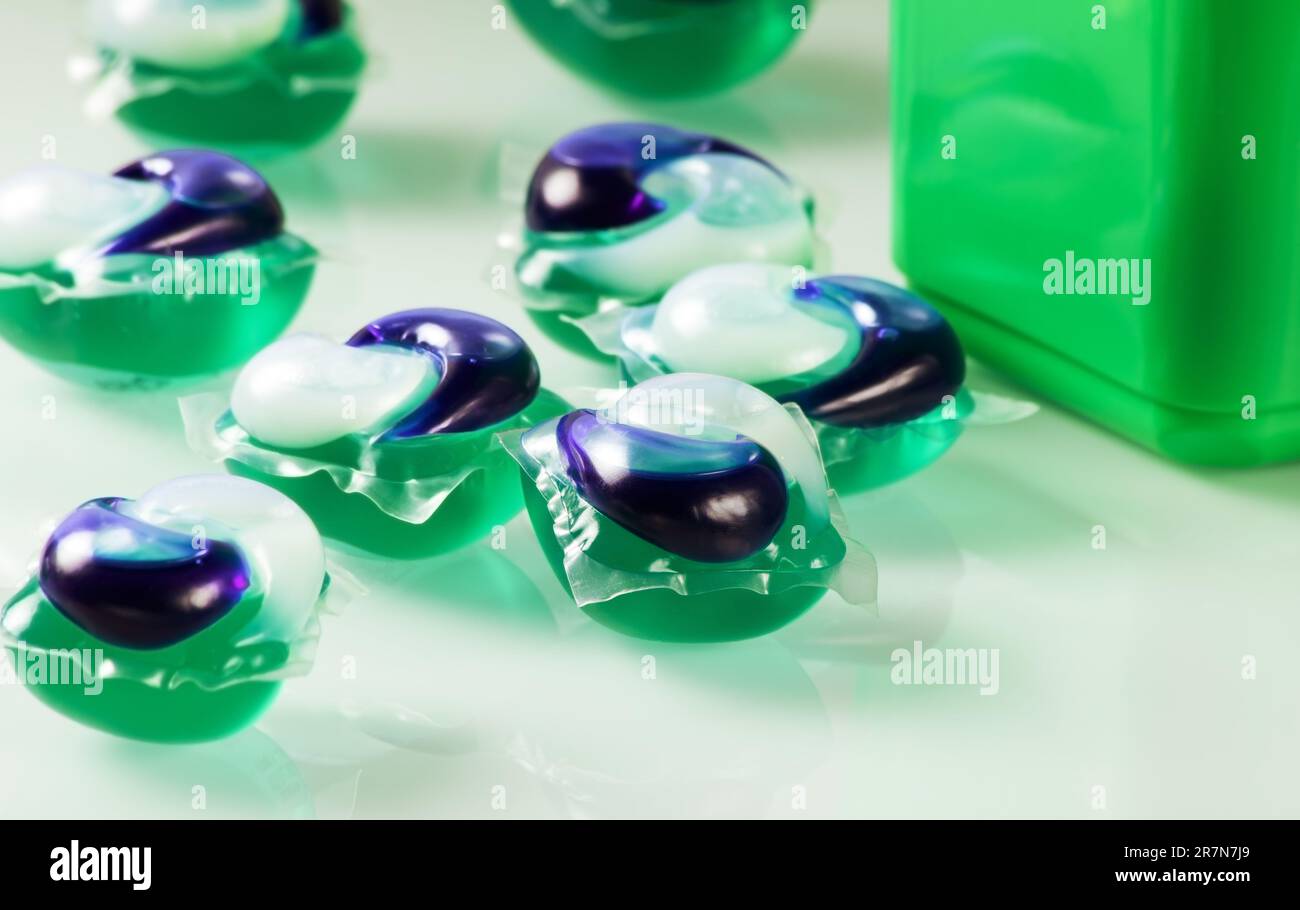 Multi-colored gel capsules for washing clothes next to a green ...