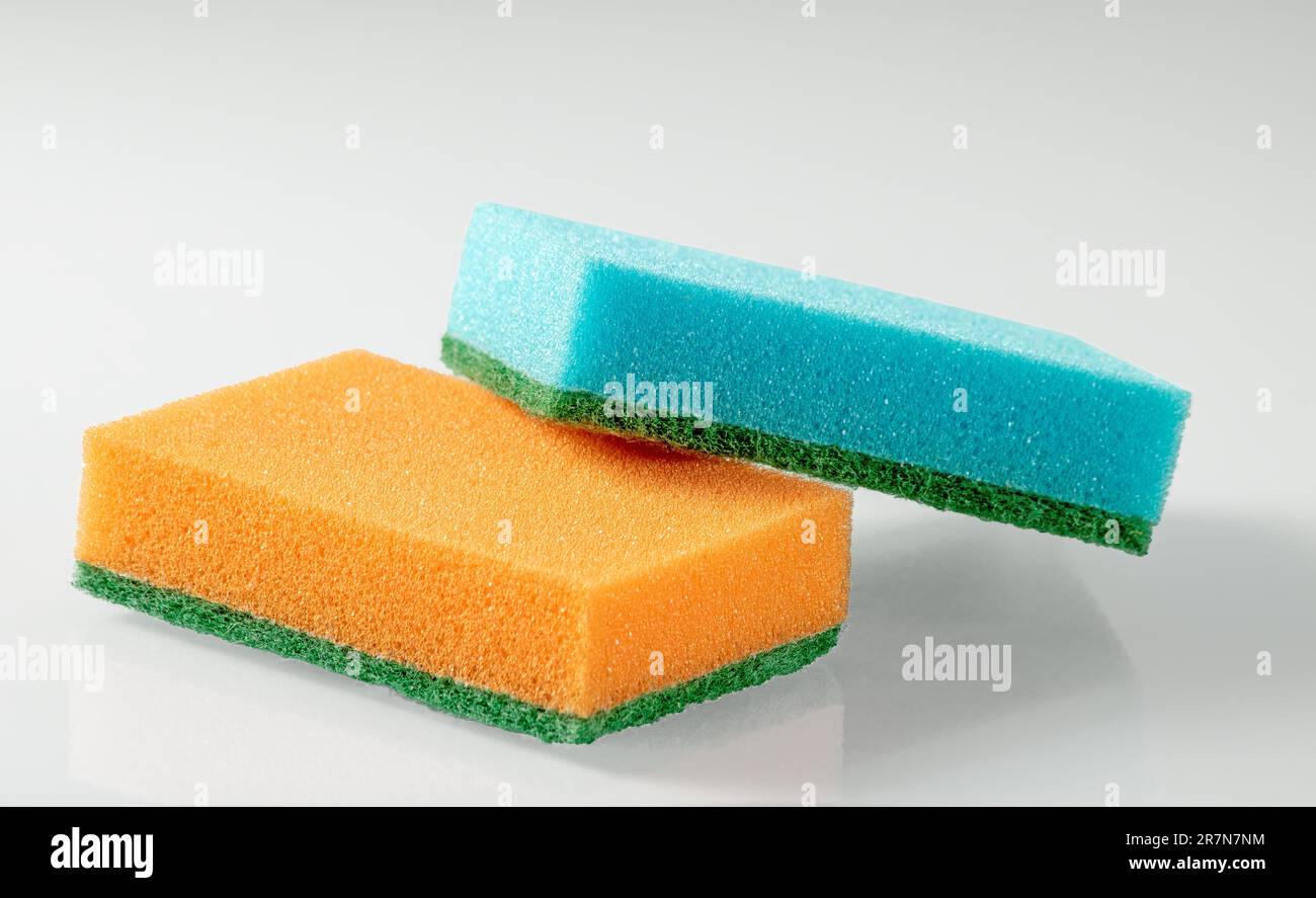 Two sponges for washing dishes in orange and blue on a white background ...