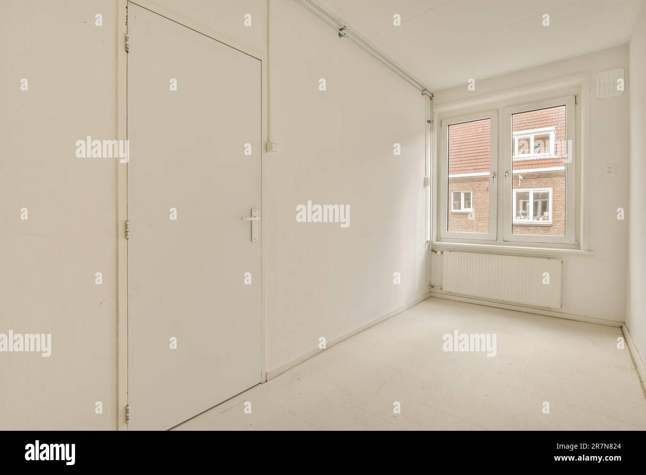 an empty room with white walls and flooring, there is a door leading to ...