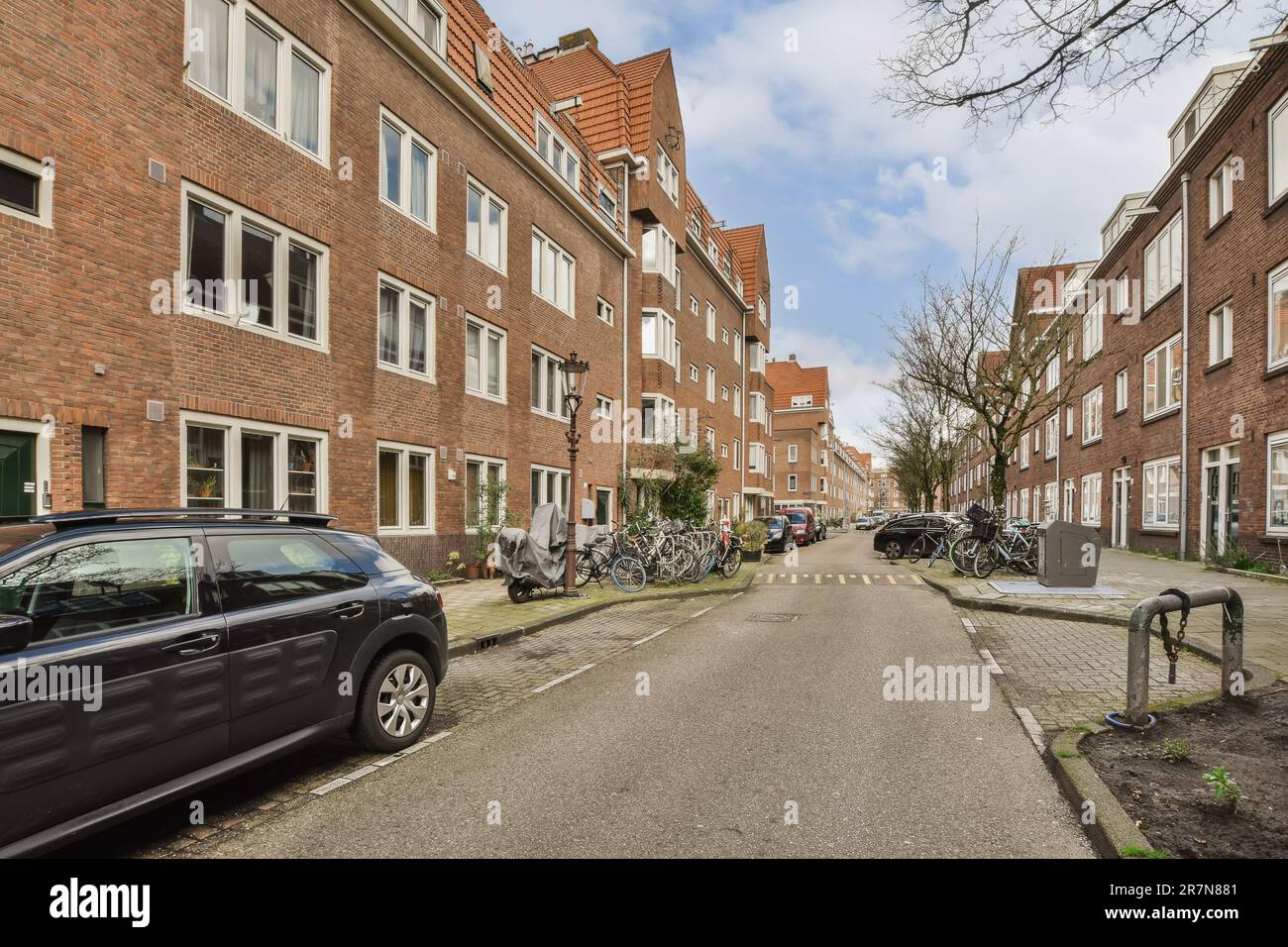 an urban street in the netherlands with parked cars and bicycles on ...