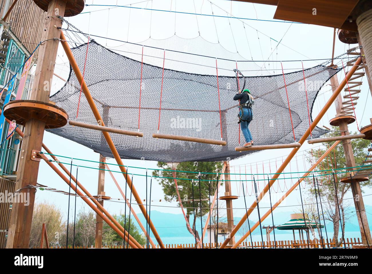 Teenage teen girl in climbing harness equipment, green sports safety ...