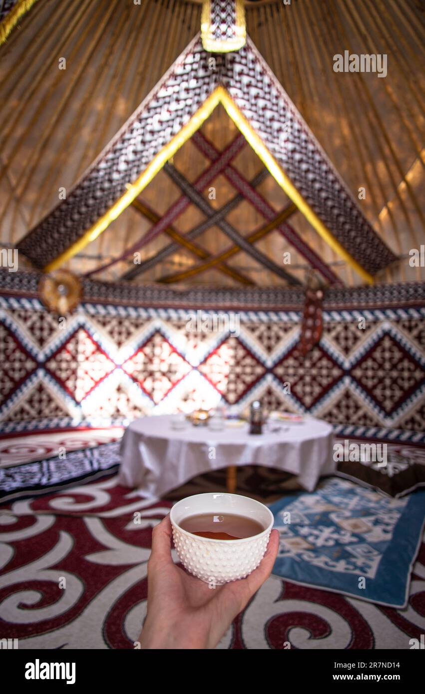 a cup of tea in a man's hand behind a dastarkhan in the Kazakh national ...