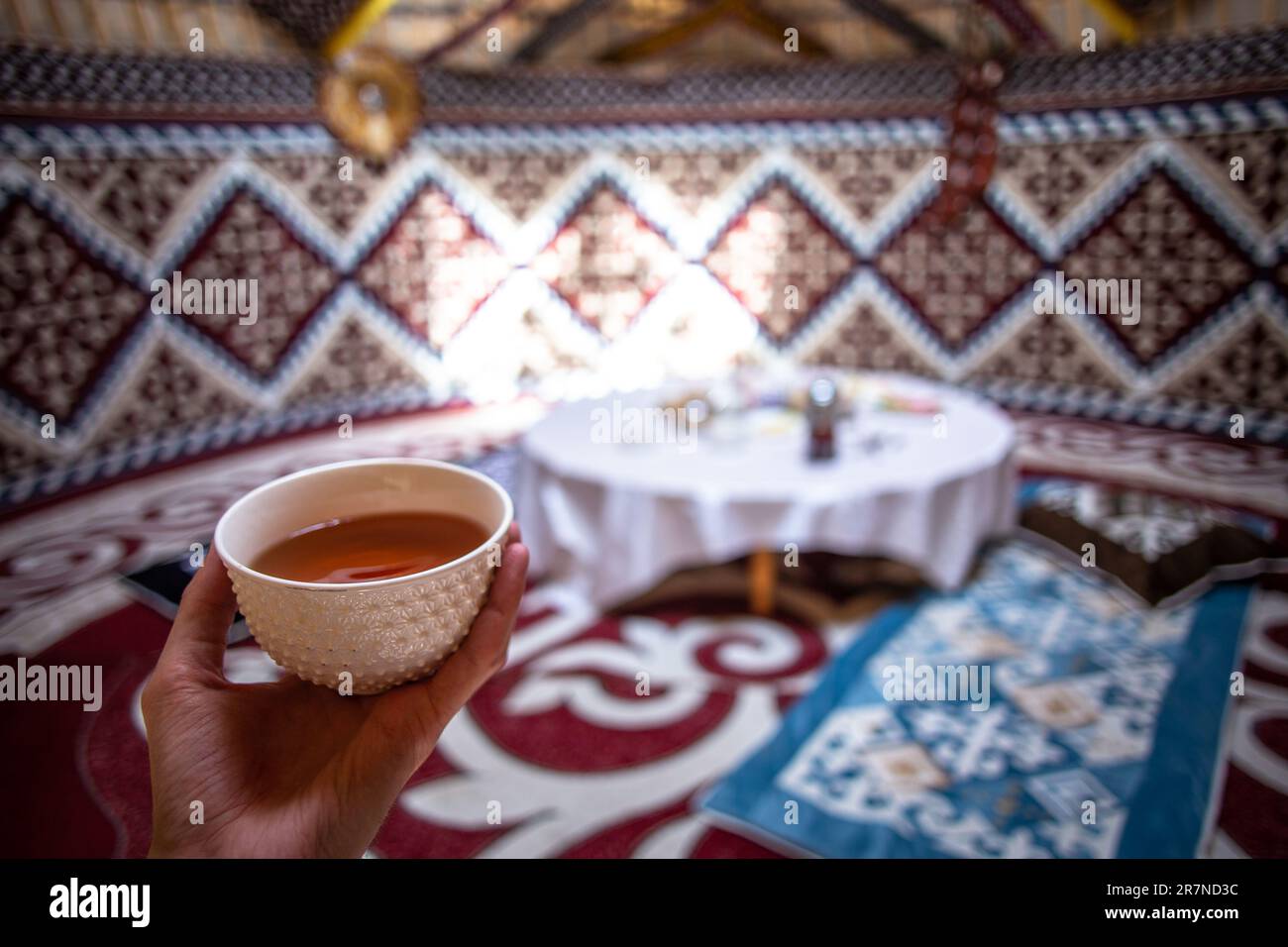 a cup of tea in a man's hand behind a dastarkhan in the Kazakh national ...