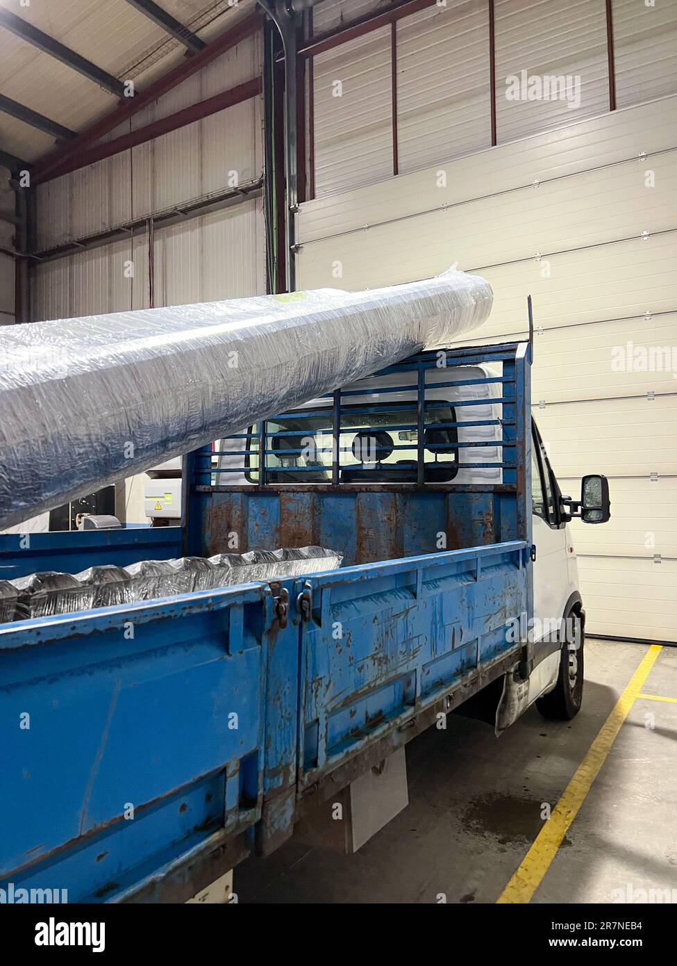 A large, white truck carrying industrial materials is parked in a ...