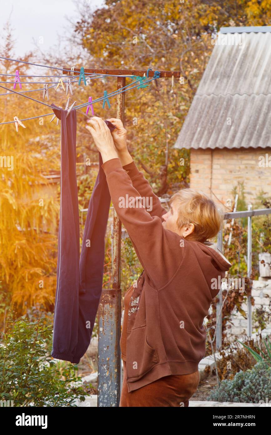 Laundry woman hangs clean wet cloth on clothes dryer after washing at ...
