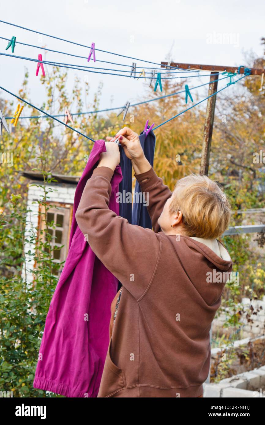 Laundry woman hangs clean wet cloth on clothes dryer after washing at ...