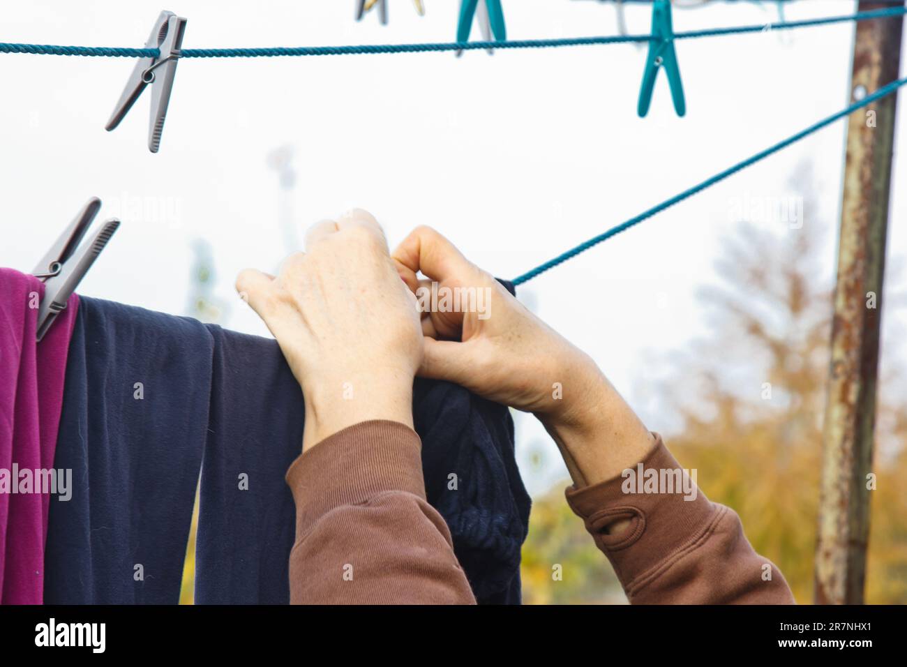Laundry woman hangs clean wet cloth on clothes dryer after washing at ...