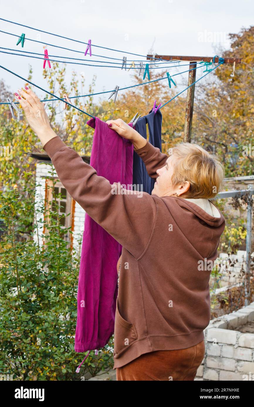 Laundry woman hangs clean wet cloth on clothes dryer after washing at ...