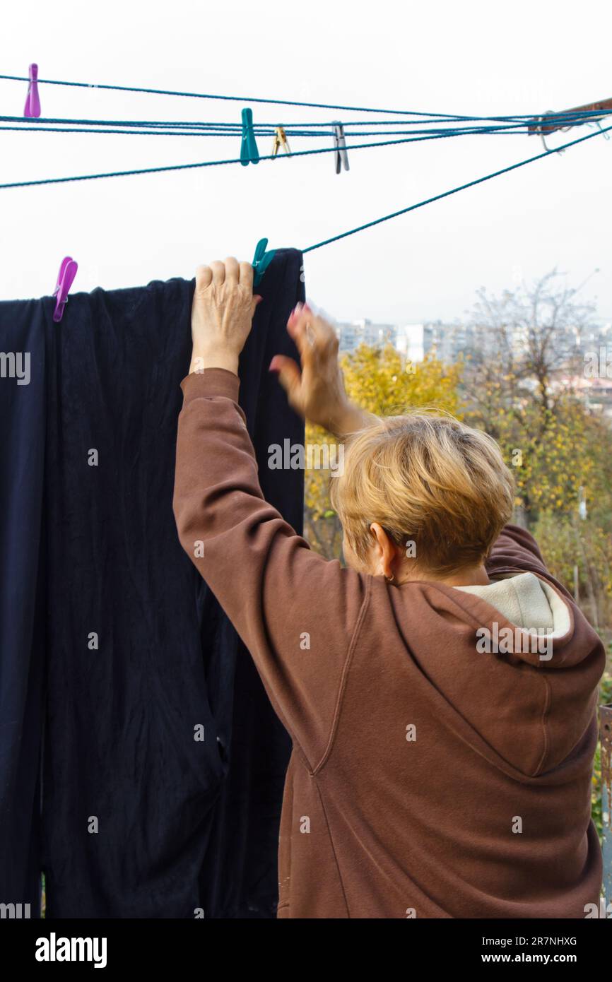 Laundry woman hangs clean wet cloth on clothes dryer after washing at ...