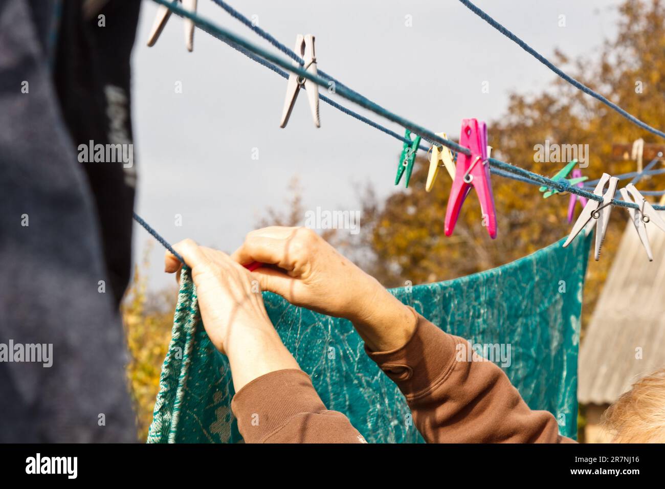 Laundry woman hangs clean wet cloth on clothes dryer after washing at ...