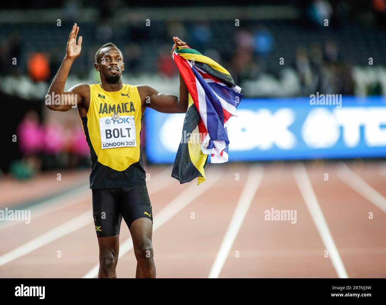Usain Bolt on the day of his farewell, saluting and with the flag of ...