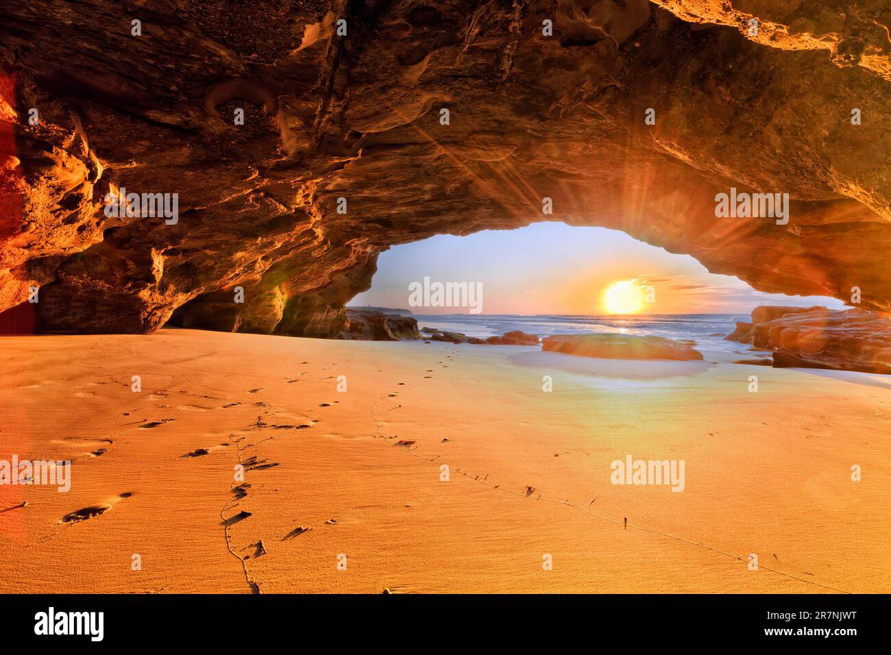 Bright sunrise over Pacific ocean from inside sea cave in Caves beach ...