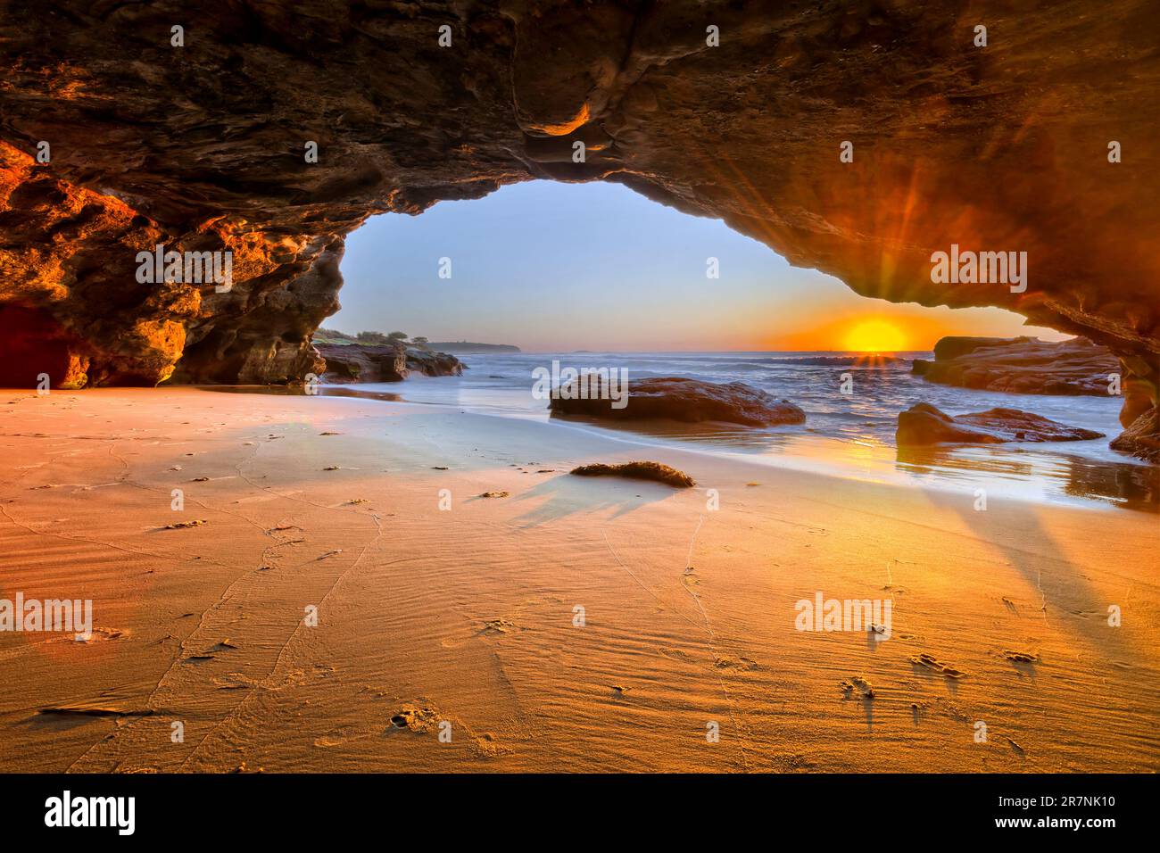 Bright rising sun shining to sea cave on Pacific coast of Australia at ...