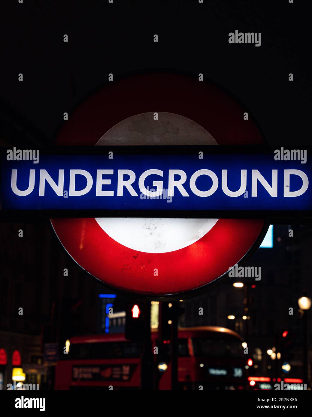 A vibrant illuminated underground sign with cars driving around it ...