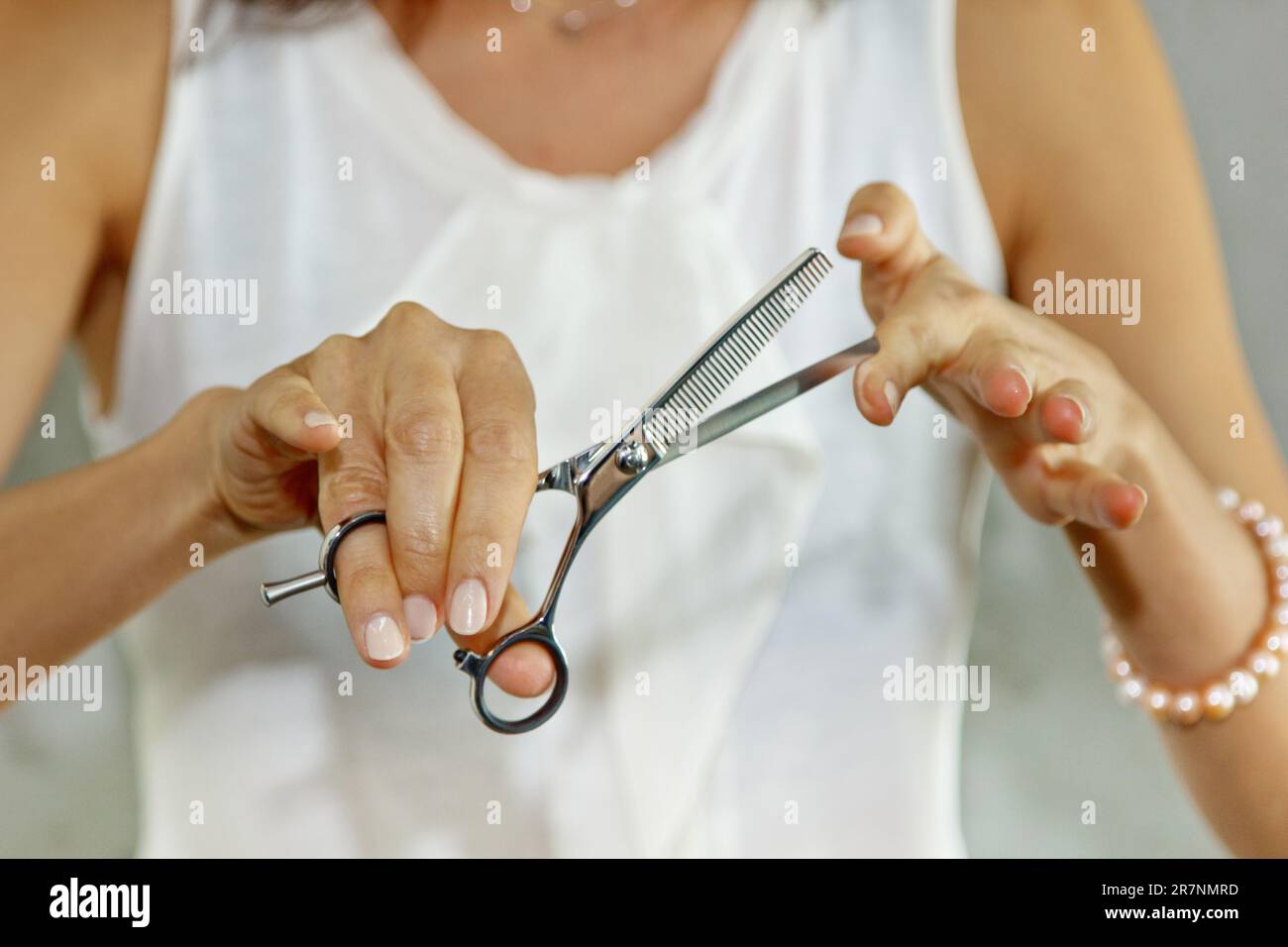 Young girl hairdresser holds scissors on outstretched hand to the ...