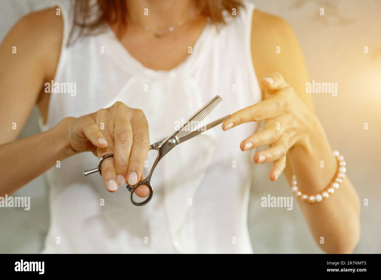Young girl hairdresser holds scissors on outstretched hand to the ...