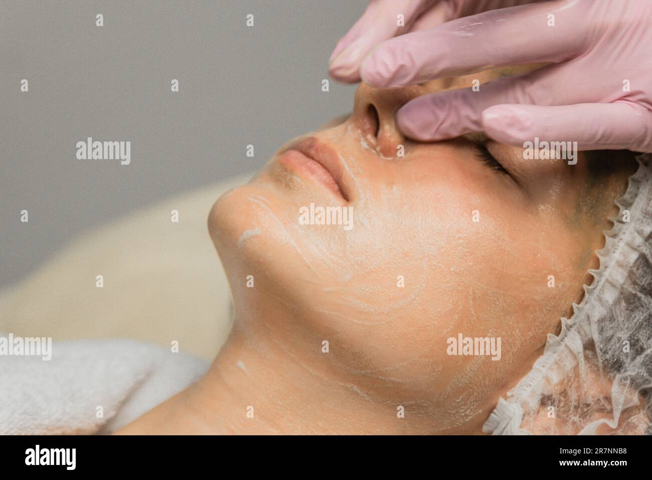 concept beautician. The hands of a cosmetologist put cream on the face ...