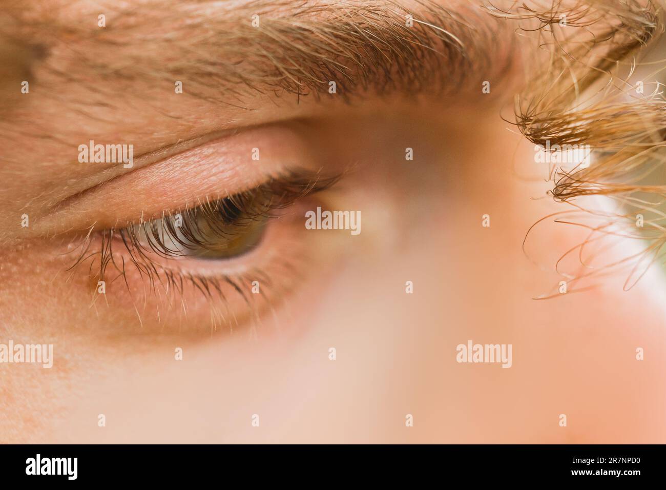 male eye close up. a curl of curly hair hangs over a man's face ...