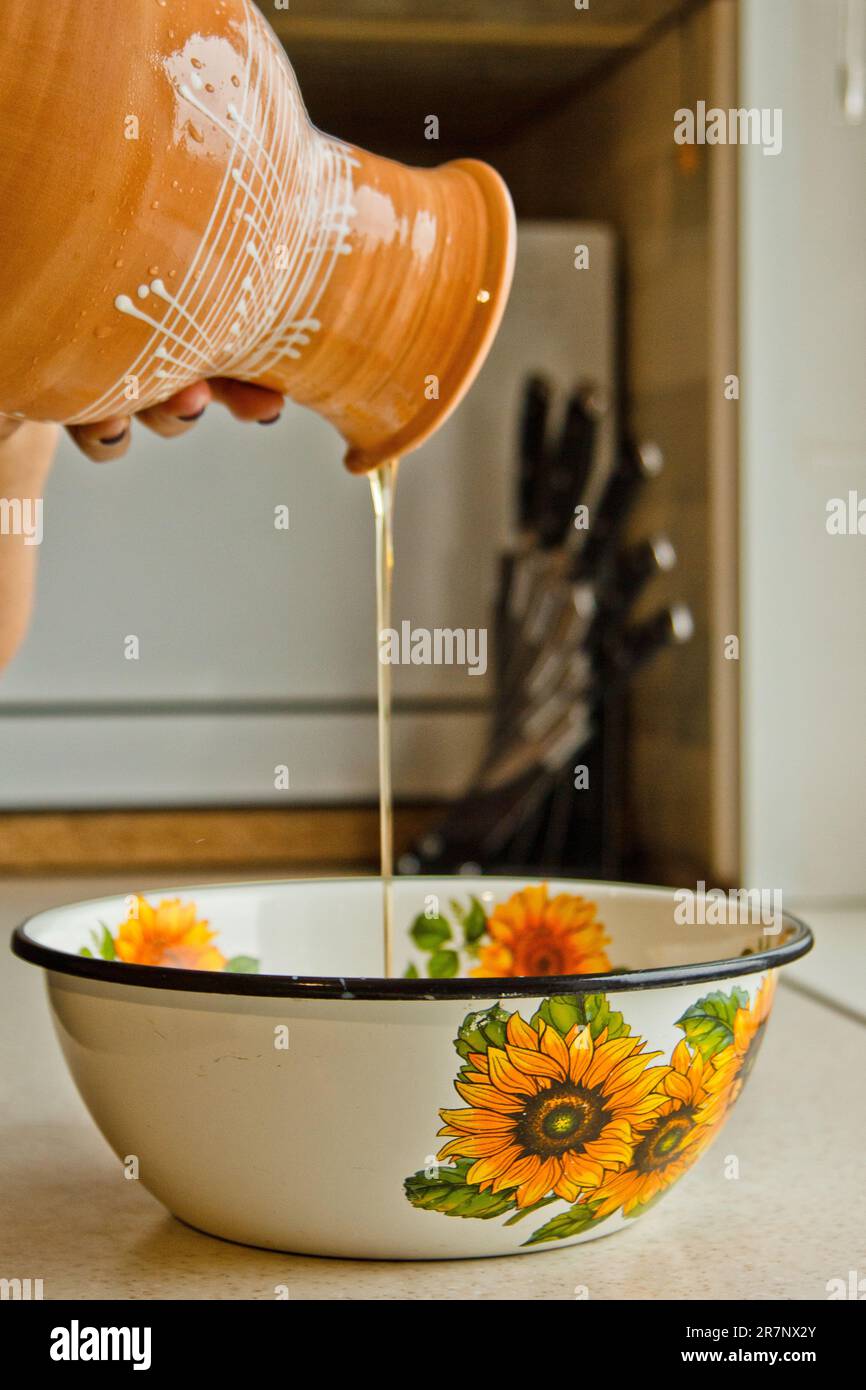 female hand pouring ceramic ewer oil into a metal bowl. painted in ...