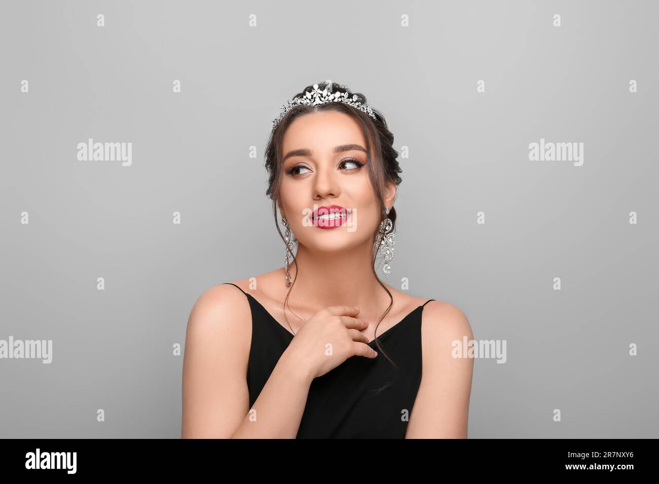 Beautiful young woman wearing luxurious tiara on light grey background ...