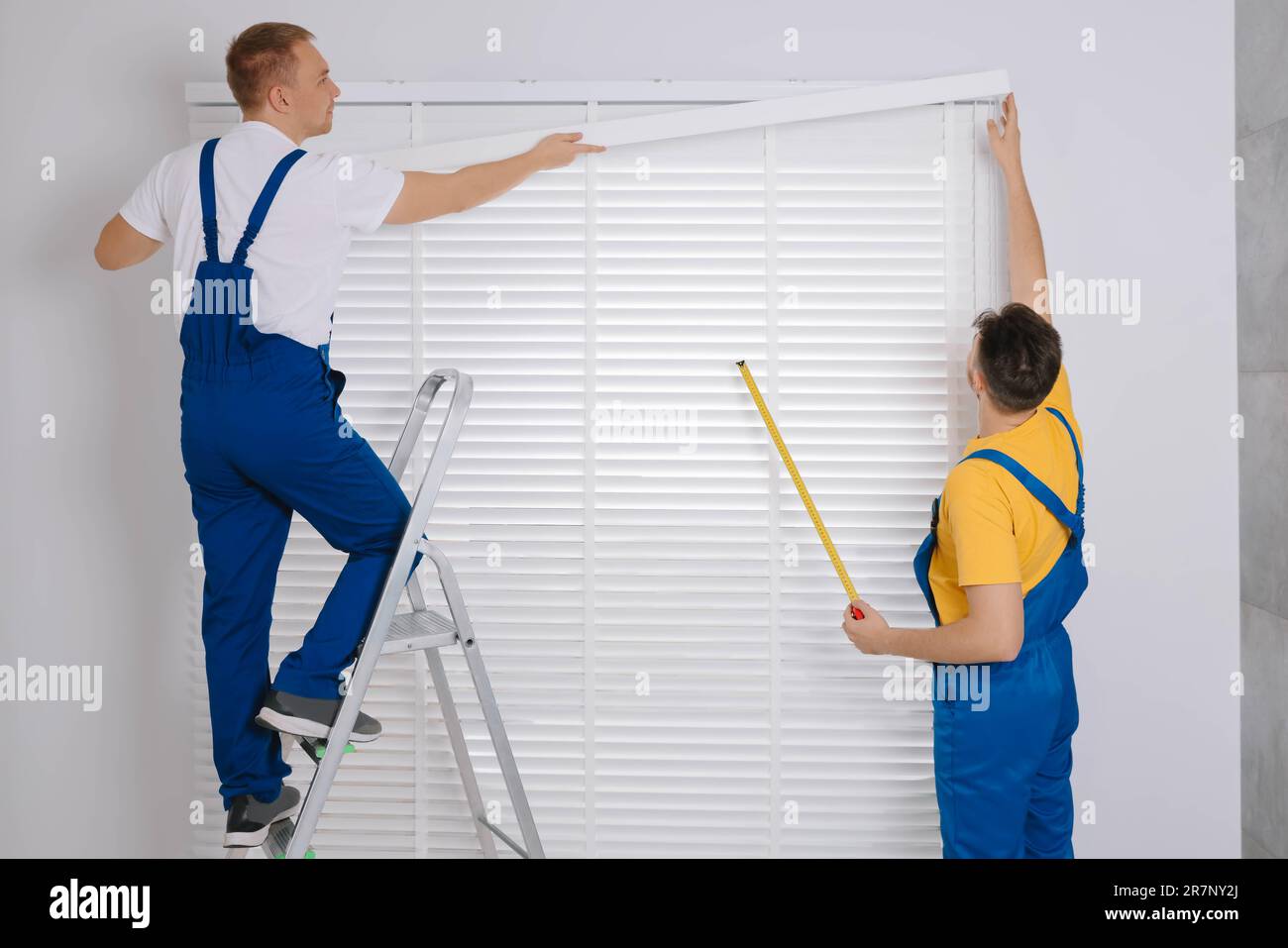 Workers in uniforms installing horizontal window blinds indoors Stock ...