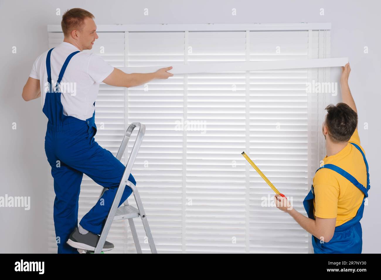 Workers in uniforms installing horizontal window blinds indoors Stock ...