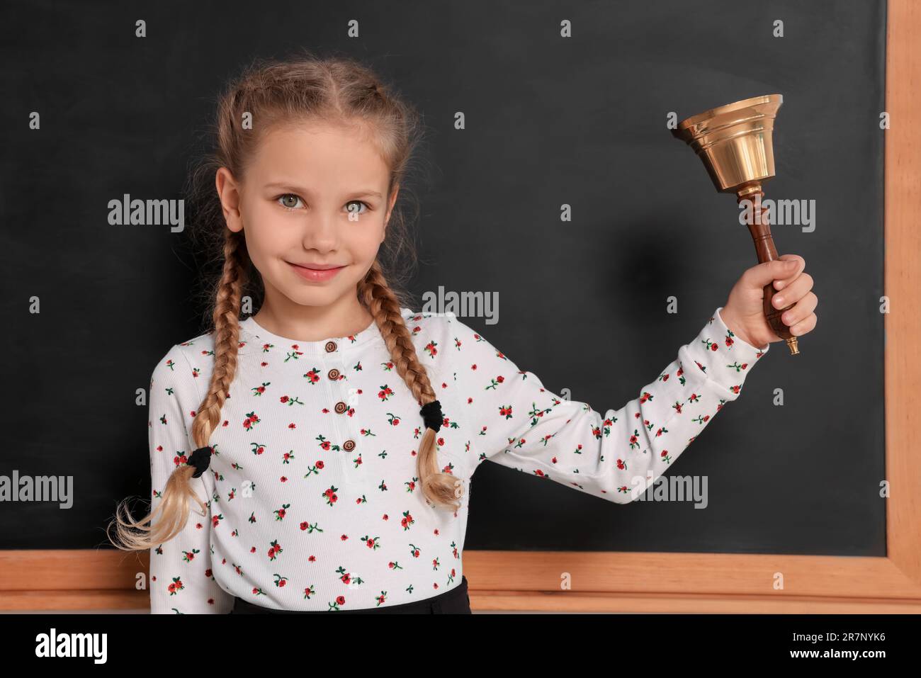 Pupil with school bell near black chalkboard in classroom Stock Photo ...