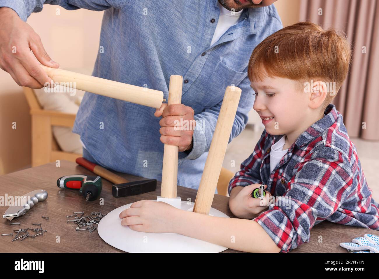 Father teaching son how to make stool indoors, closeup. Repair work ...